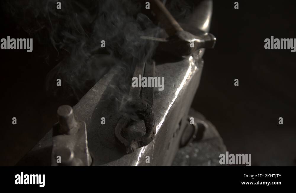 A blacksmith instruments on the anvil with a steam vapor comes off them ...