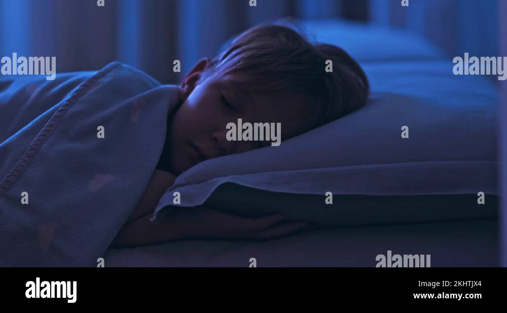 8 years old boy sweetly sleeping in his crib. Face close-up of a ...