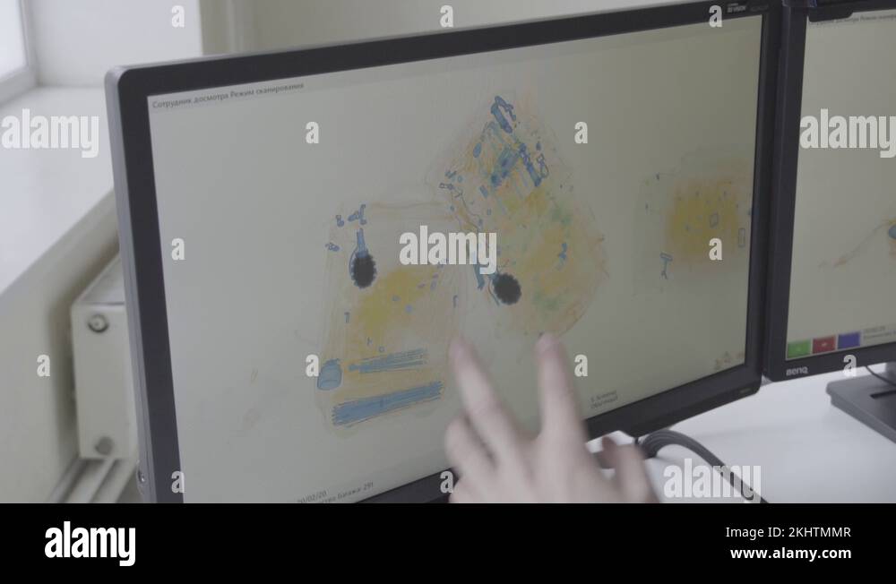 Male airport security officer pointing at dangerous item on xray ...