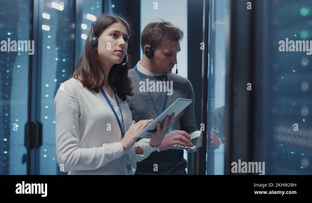 Female and male data operators monitoring open rack server cabinet ...