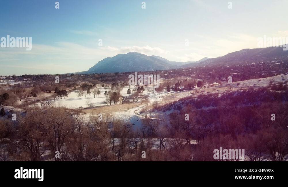 A pink lens flare over an aerial towards a mountain in the snowy ...