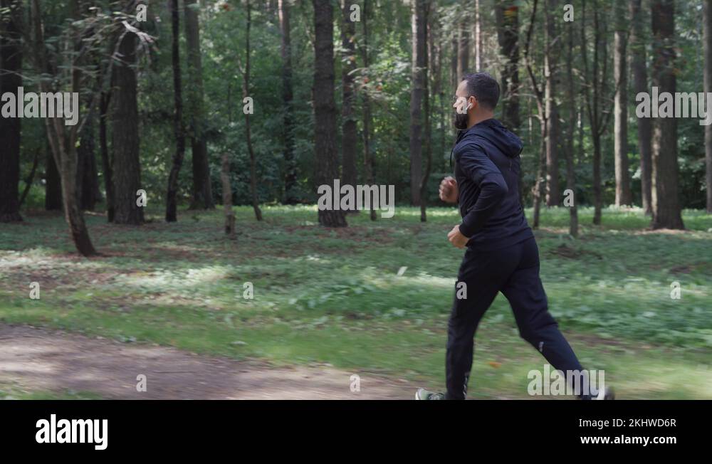 Man running through summer forest, camera following, runner in wireless ...
