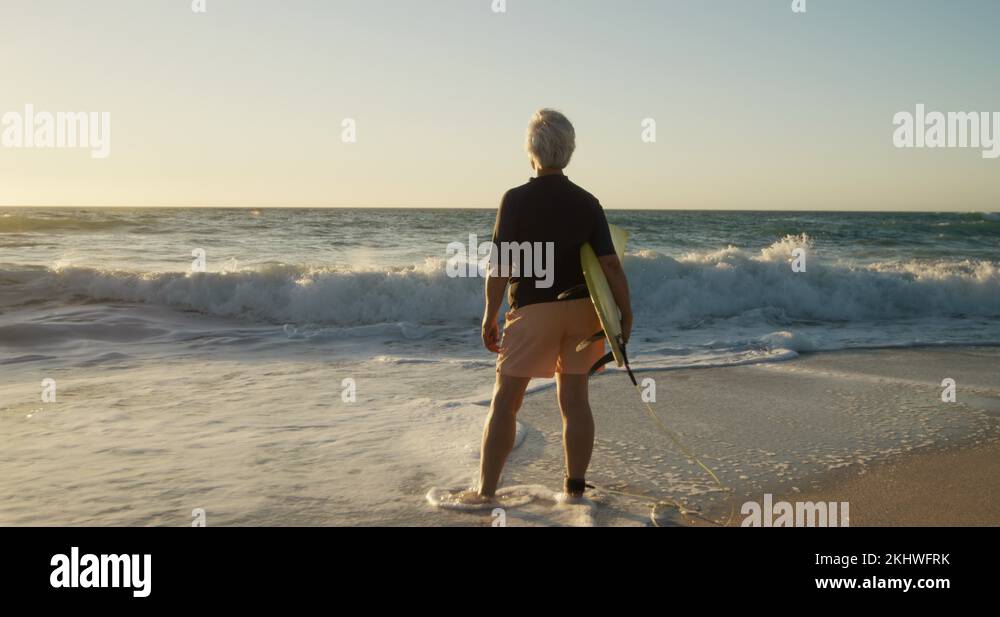 Rear view old man with surfboard at the beach Stock Video Footage - Alamy