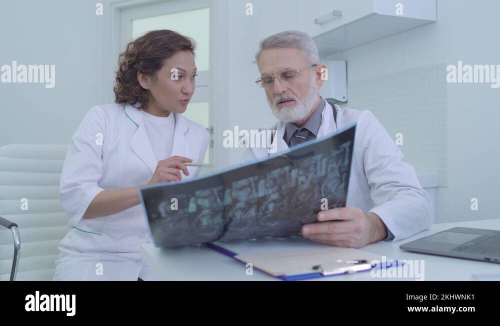 Two colleagues examining patients mri scan discussing injury treatment ...
