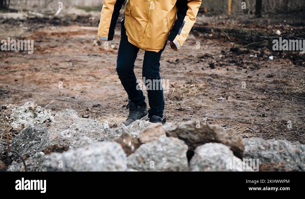 The boy is walking on a hill of stones. Close- up of the legs. Hard way ...