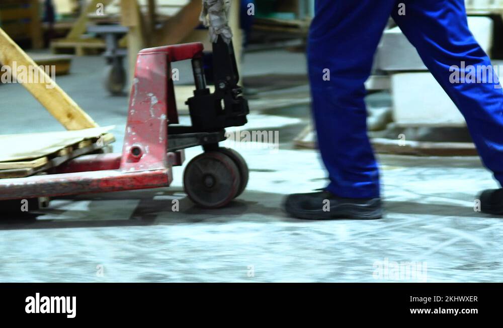 Adult Male Warehouse Worker Pushing Pallet Truck On Factory Floor. Low ...
