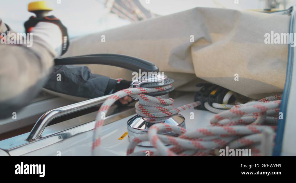 Sailing yacht yachtsman rotates halyard winch with yacht ropes Stock ...
