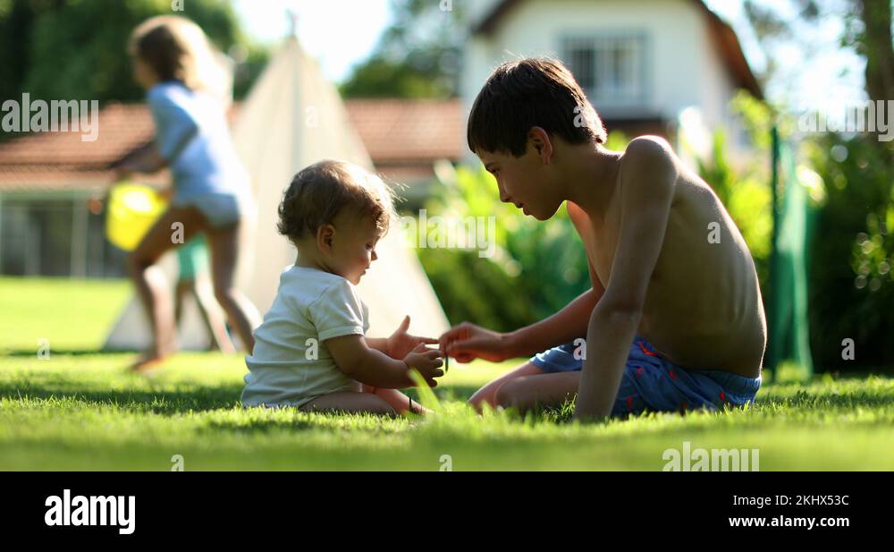 Two brothers interacting together outside in home backyard. Older ...