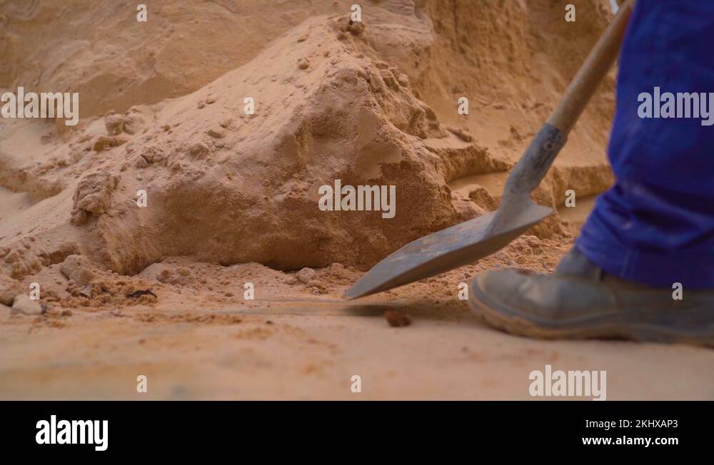 Worker use the shovel and fill the wheelbarrow with sand for ...