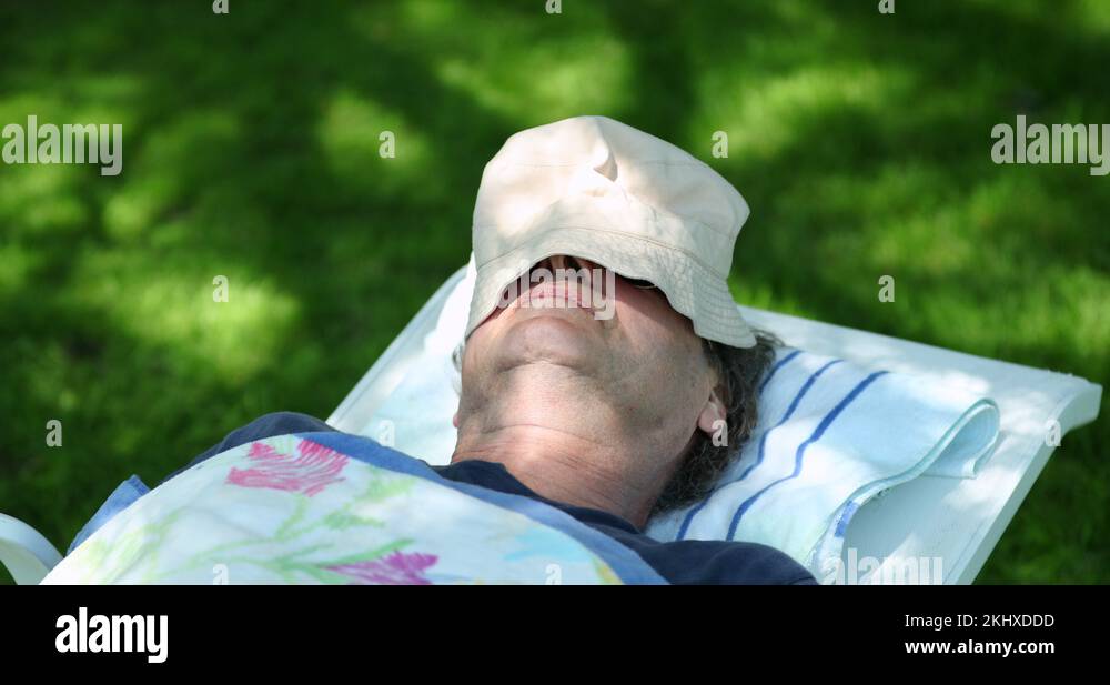 Older man napping outside covered by hat. Retired senior person ...