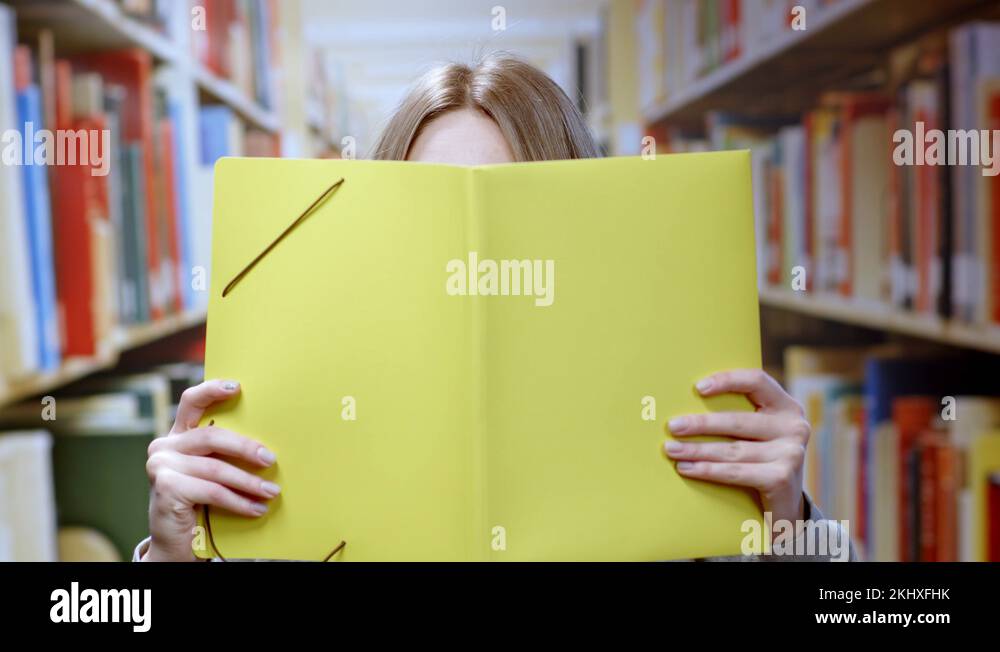 Curious and smart young student girl reading a book in the library ...