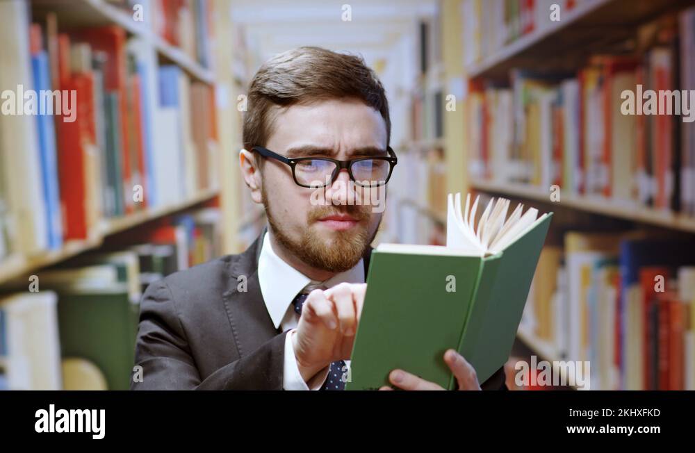 Handsome amazed man studying in the library reading books finds ...