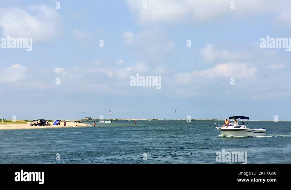 Small power boat with shirtless guy seated on bow moves slowly through ...