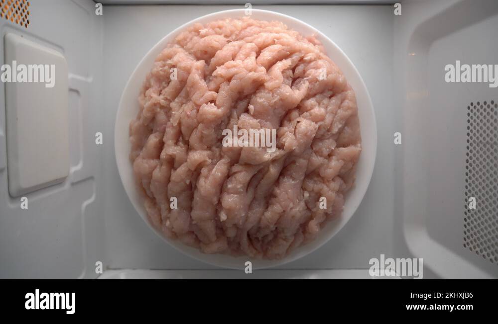 Plate with raw ground chicken meat rotating in microwave top view Stock ...
