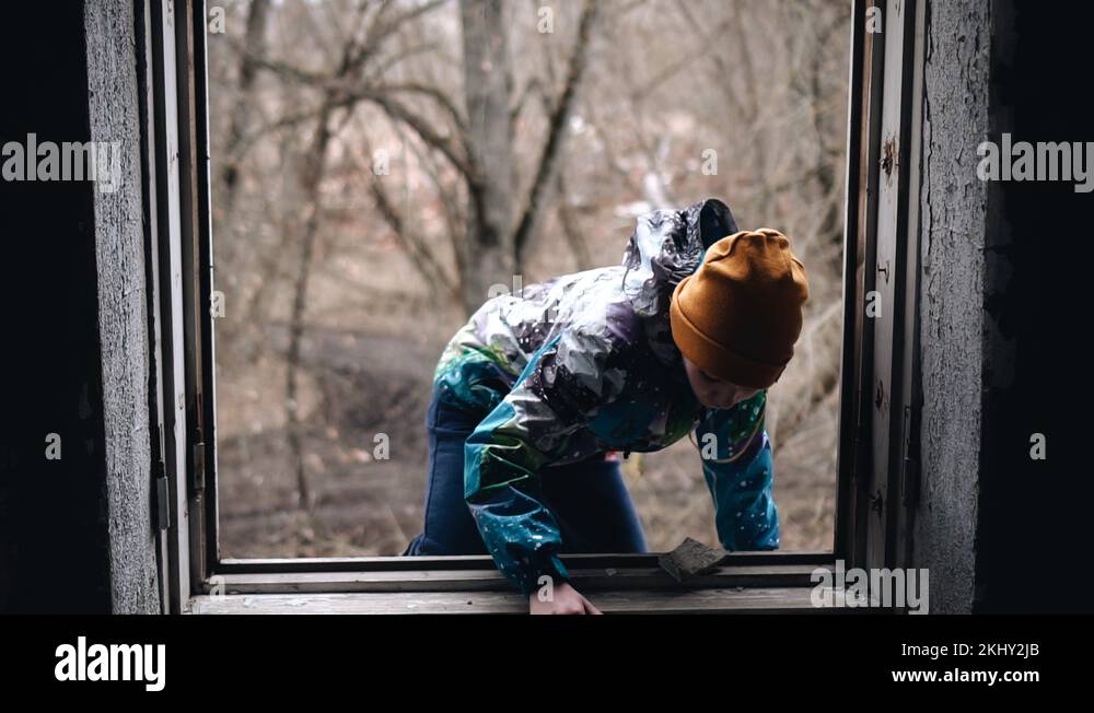 The guy climbs in the window of an old house. Young researcher Stock ...