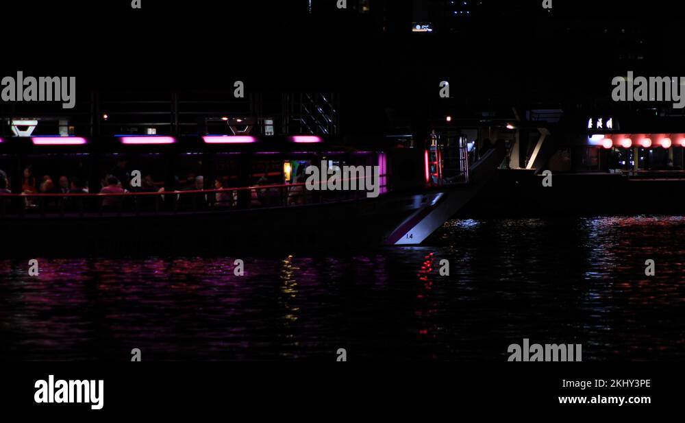 Moving neon boat nat the bay area in the urban city in Tokyo at night ...
