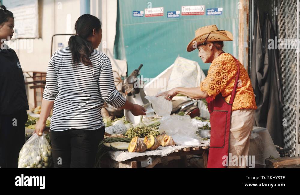 Old woman packing and selling vegetables on a street market in Thailand ...