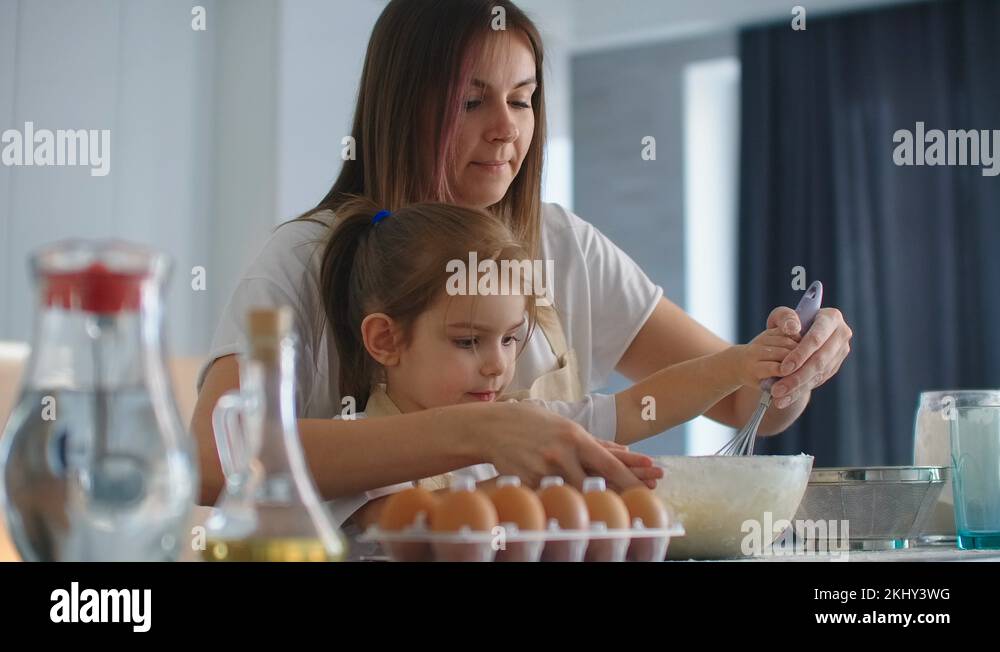 A smiling mother helps her daughter learn how to make a pie. Teach a ...