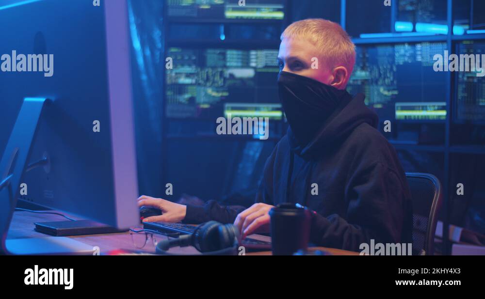 Caucasian woman hacker with blond short hair and masked face sitting in ...