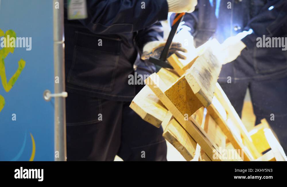 Two workers in overalls disassembling wooden pallet in warehouse, use ...