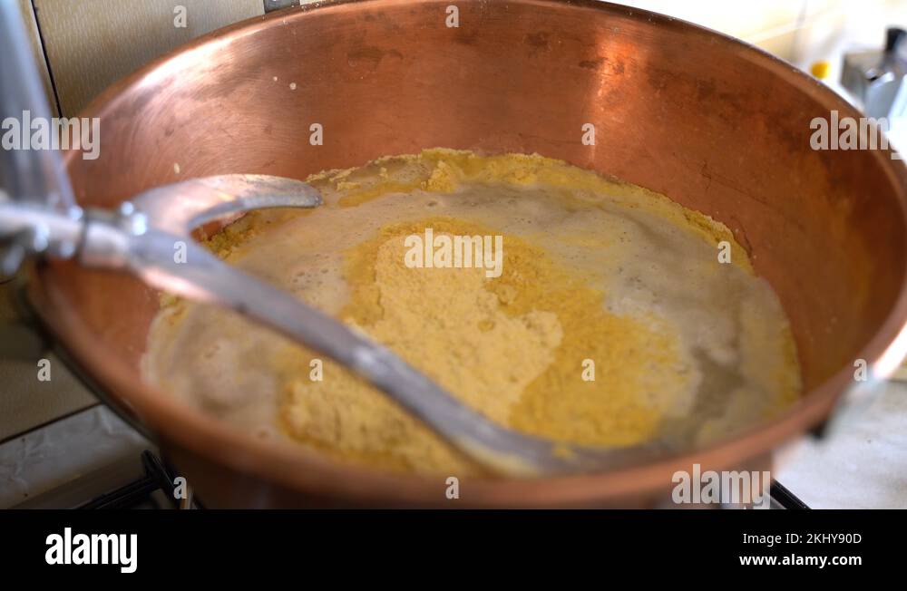 Typical copper cauldron with boiling water on the stove and yellow corn ...