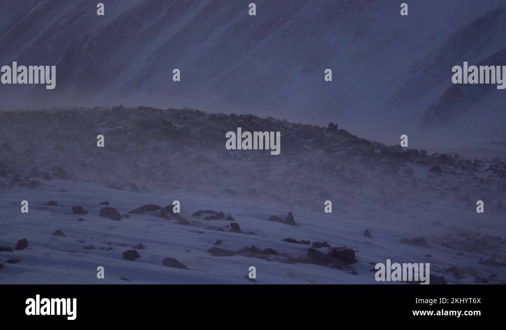 cold wind blowing snow in winter over dark mountain peak string rocks ...