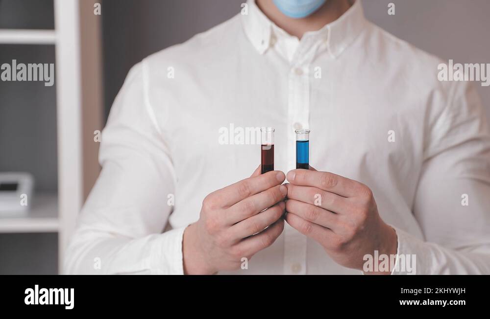 Close up laboratory doctor holds two test tubes of red and blue colors ...