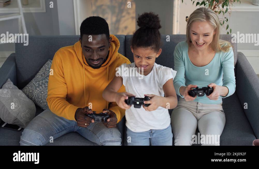 Multinational family, parents and daughter playing a game console ...