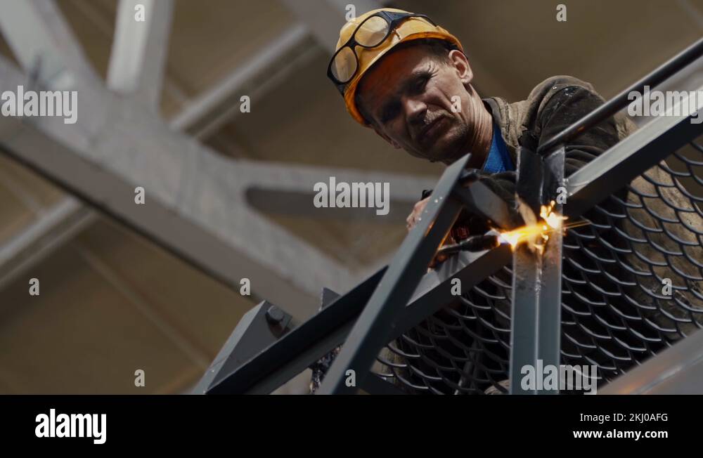Factory Man in Orange Helmet Soldering Metal Structure at the Modern ...