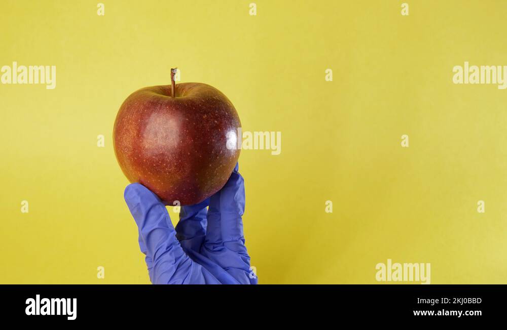 Injection into an apple, yellow background. Genetic modified foods ...