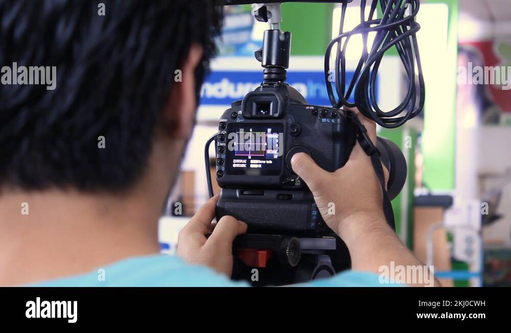 Young man adjusting the DSLR camera menu options in its screen on film ...