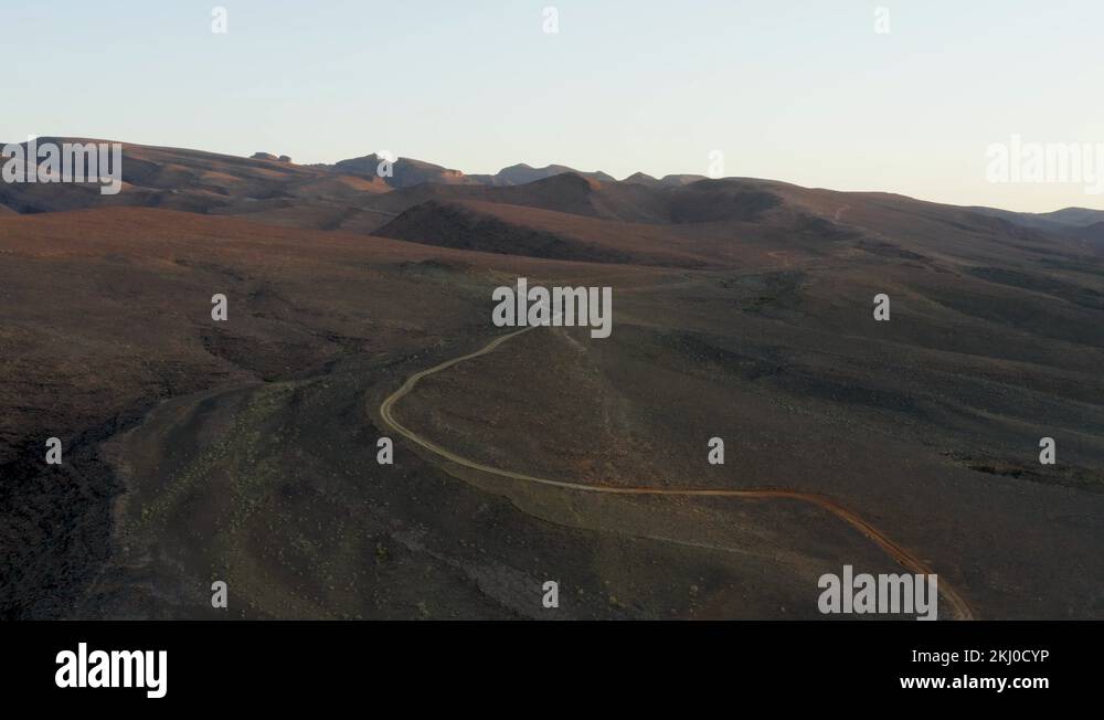 An aerial of a desolate but colorful desert, bisected by a single ...