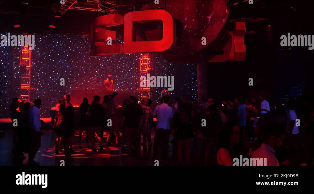 DJ mixing music for dancing people at console desk in disco night club ...