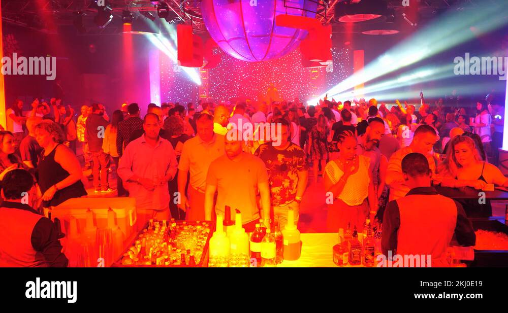 DJ mixing music for dancing people at console desk in disco night club ...