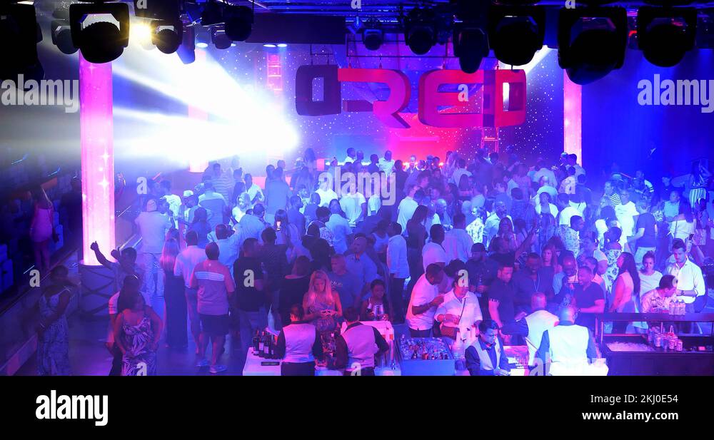 DJ mixing music for dancing people at console desk in disco night club ...