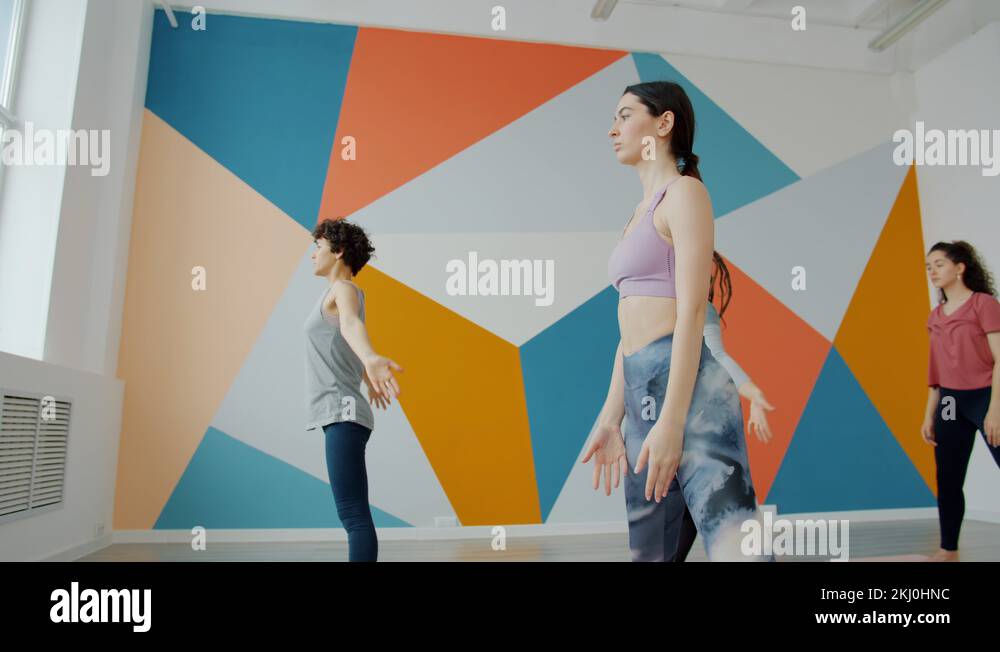 Girls and guy bending forward during yoga practice in spacious gym ...