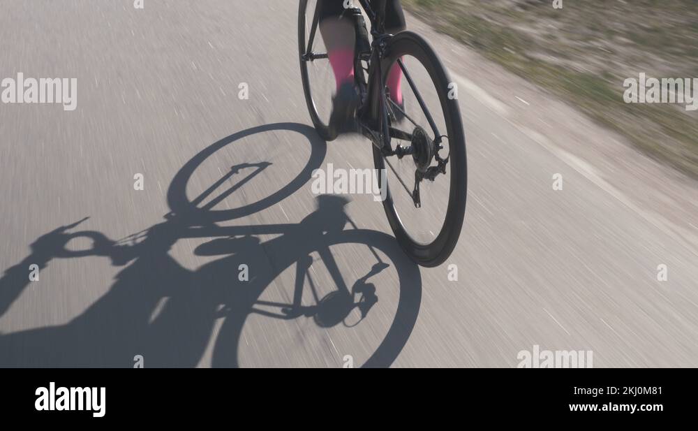 Female muscular feet are pedaling on road bike, close up. Woman riding ...