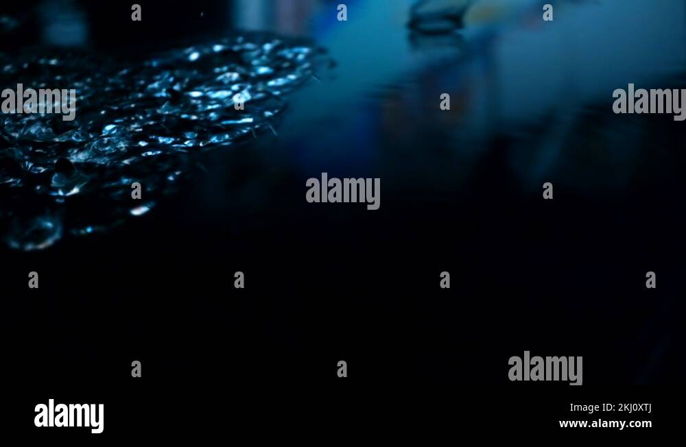 Rain drops falling into puddle on asphalt at night. City street ...