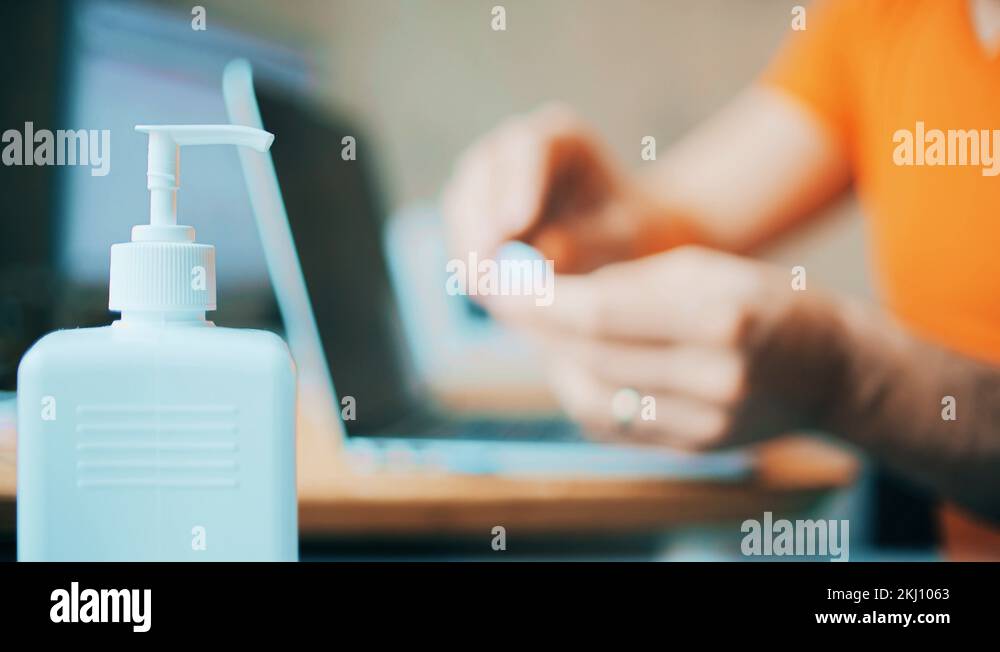 A man working from home uses disinfectant to clean his laptop ...