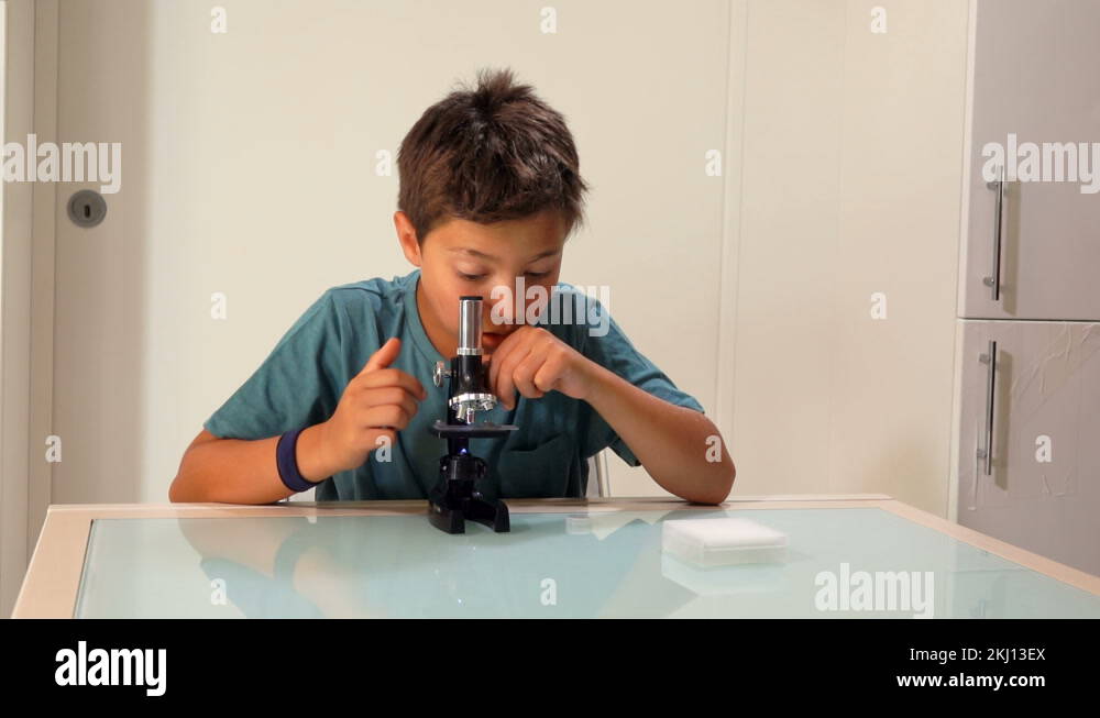 Curious dark-haired teen boy is looking through a microscope Stock ...