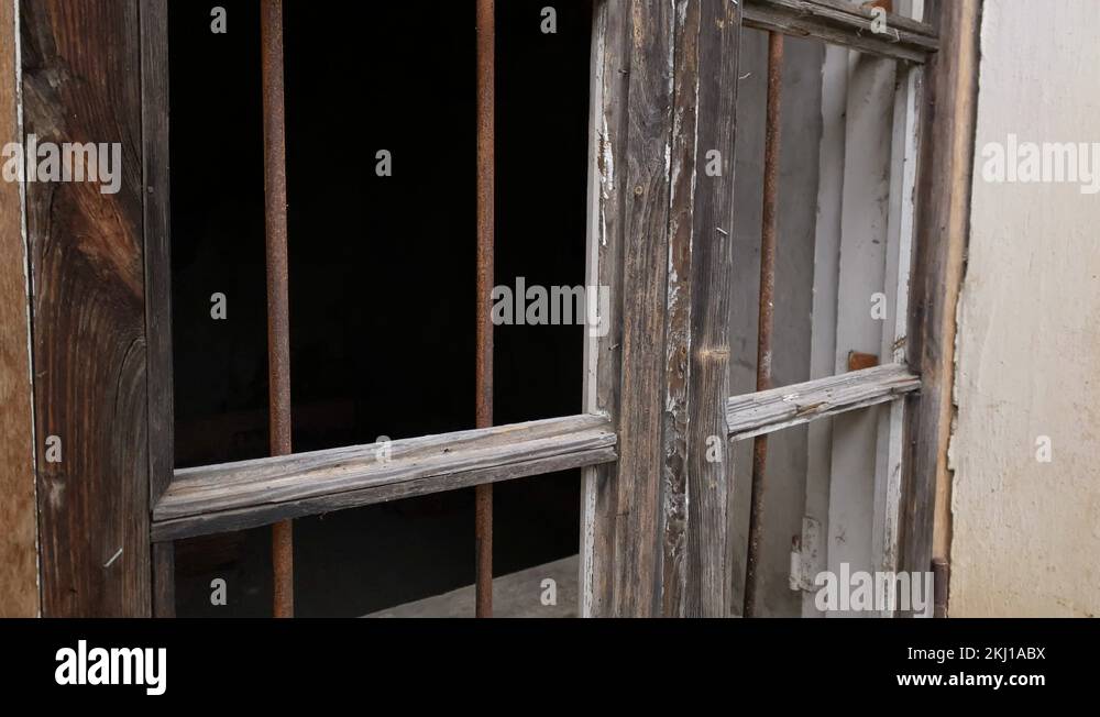 Abandoned old house stone wall, broken glass window with rusty bars ...