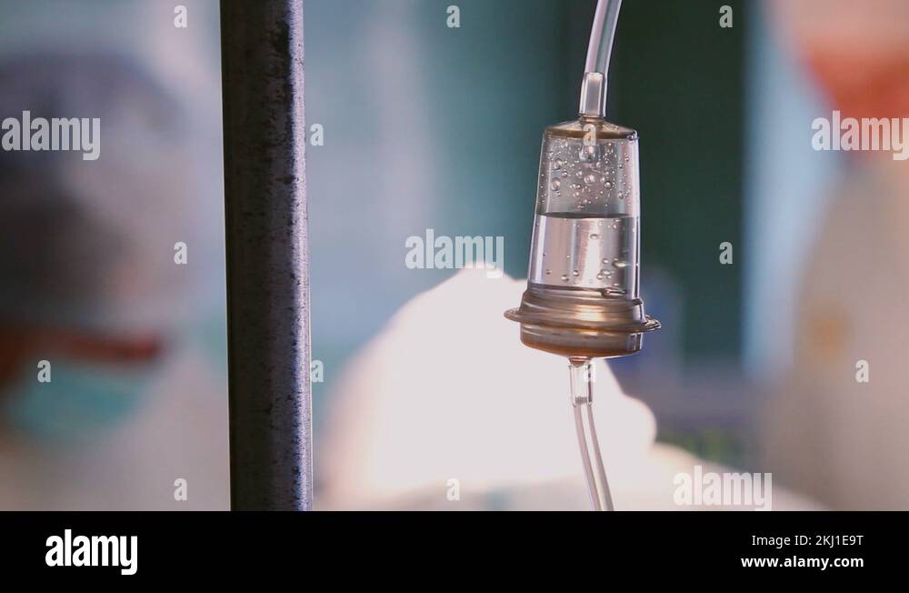 Drops of see-through liquid dripping slowly in a glassy dripper in a ...