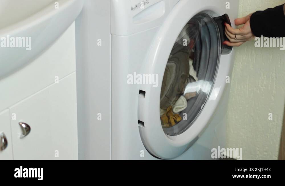 Static view of a woman opening and unloading a washing machine load ...