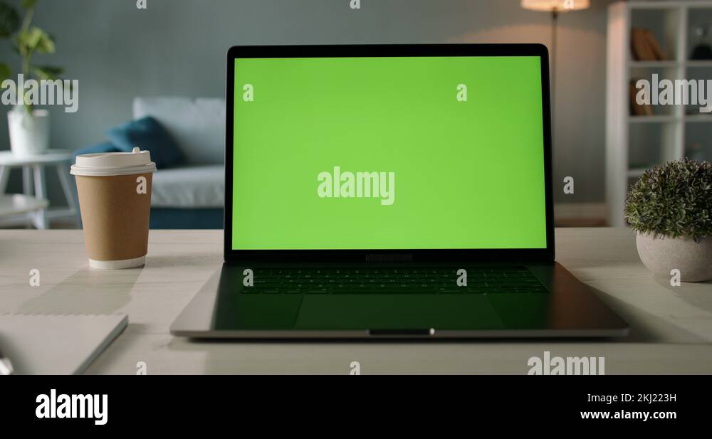 Modern laptop with mock up chroma key green screen st on desk of living ...