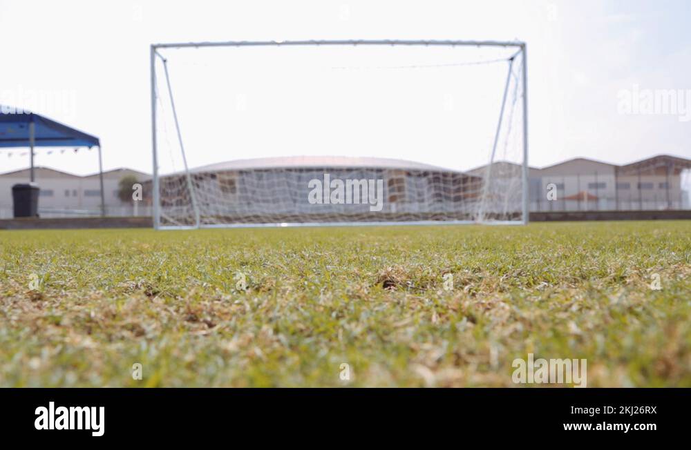 Football soccer ball roll into centre of frame with goalpost behind ...