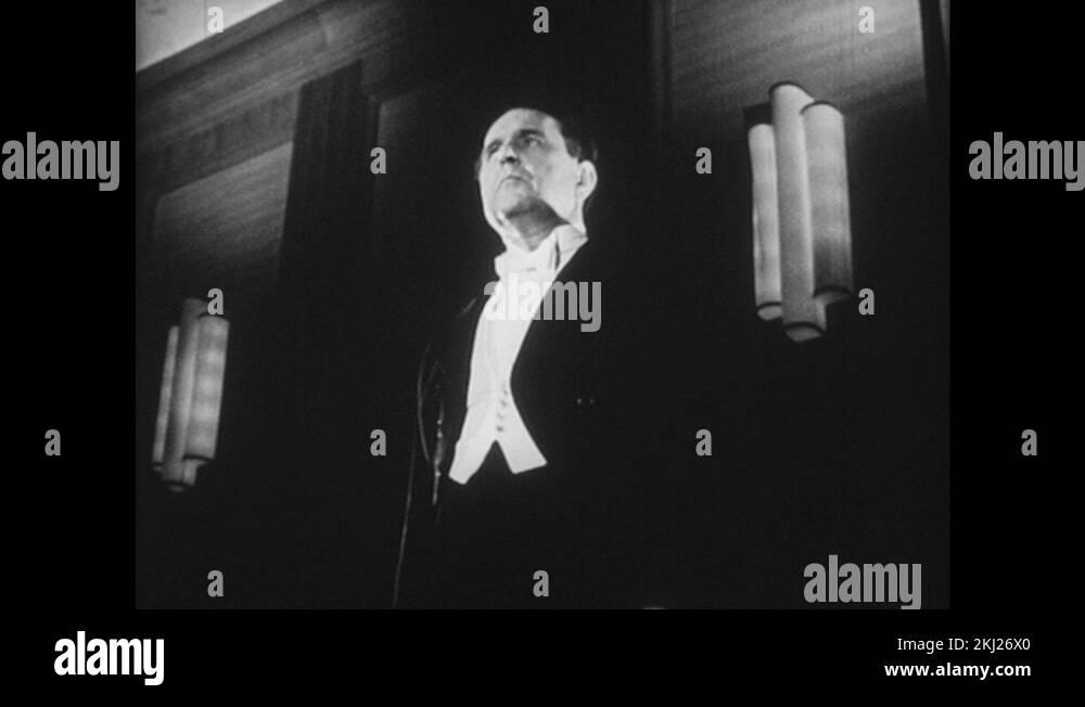 1950s: Conductor waves arms and baton. Hands flip through sheet music ...