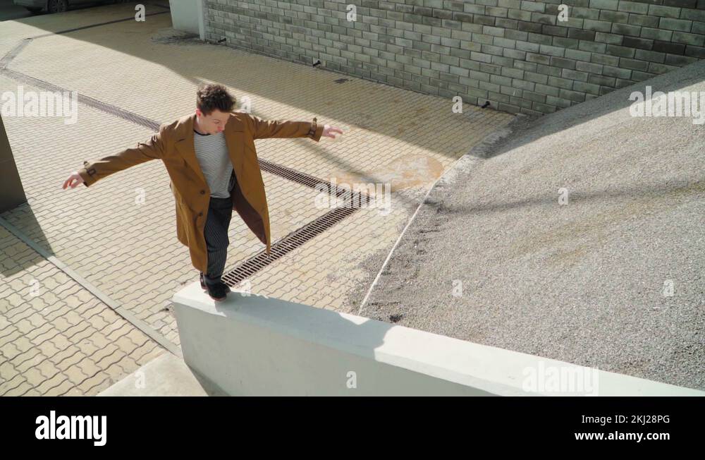 Happy Stylish Young Caucasian Guy dancing up the Parapet along the ...