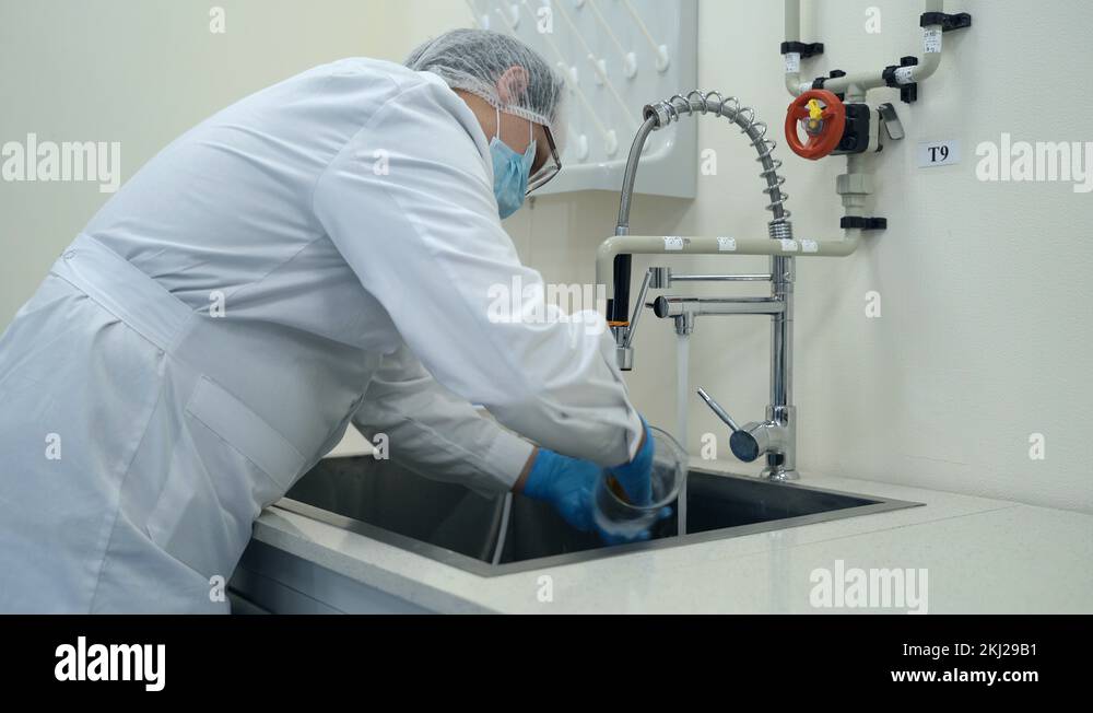 chemist washing glassware in laboratory, laboratory employee worker ...