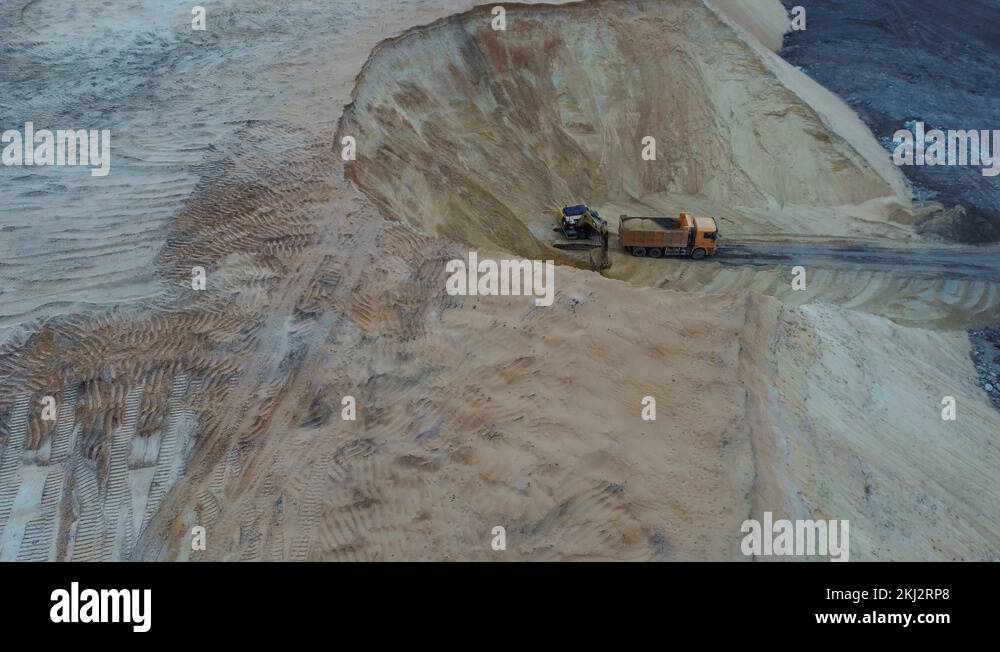 Excavator and dumper truck. Aerial view of loading sand into a truck. A ...