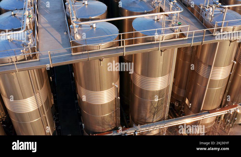 Tall stainless steel tanks connected with pipes: shiny silos in a ...